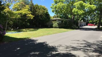 Uma entrada de casa residencial com balanço, um carro vermelho e uma casa com garagem.