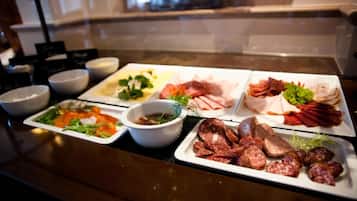Buffet com diversos pratos, incluindo carnes, queijos e saladas.