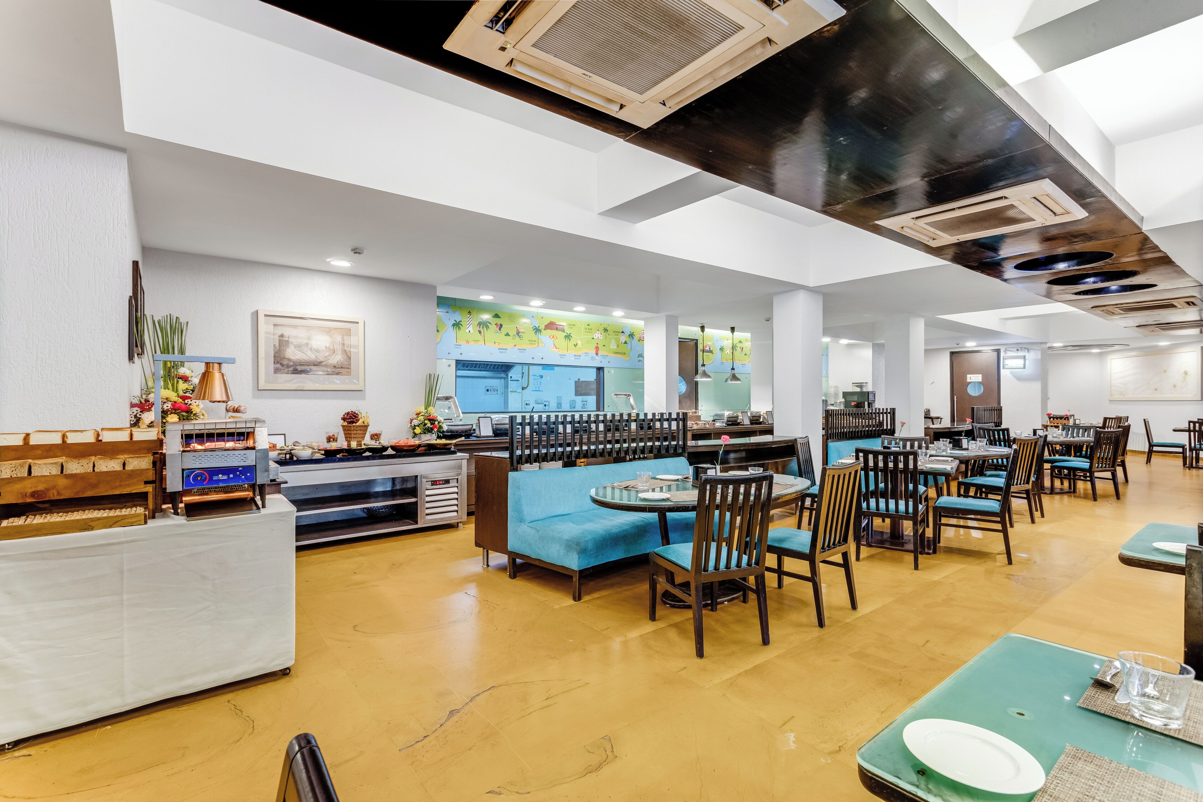 Um restaurante amplo com pé-direito alto, várias áreas de estar e cozinha central.