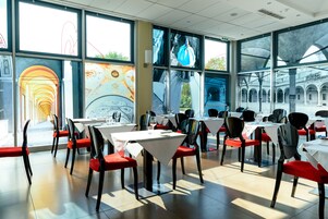 Um restaurante com mesas, cadeiras, janelas amplas e vista para o exterior.