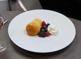 Um prato branco com um pastel, frutas vermelhas e chantilly sobre uma mesa.
