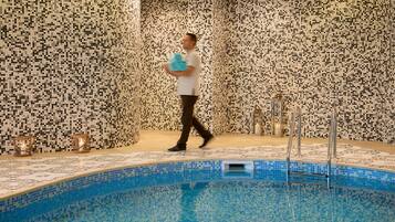 Uma área de piscina com paredes em mosaico e piso revestido.