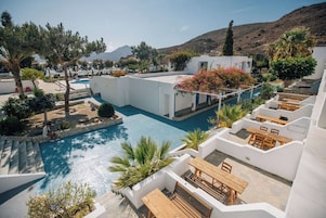 Uma área de piscina no terraço, com paredes brancas, móveis de madeira e uma vista ampla da paisagem ao redor.