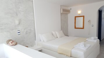 Quarto de hotel com cama, mesa de cabeceira, espelho, telefone e banheiro com banheira.