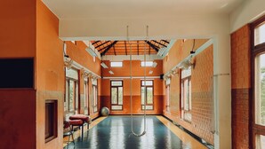 Um quarto amplo, com teto alto, grandes janelas e uma área central para exercícios.