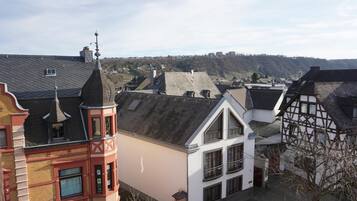 Uma cidade europeia tradicional com uma variedade de estilos arquitetônicos, incluindo um edifício vermelho de destaque com uma torre e um edifício branco com varanda.