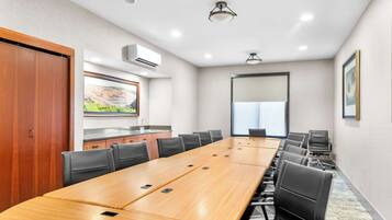 Uma sala de conferências com uma longa mesa de madeira, cadeiras pretas e um grande janelão.