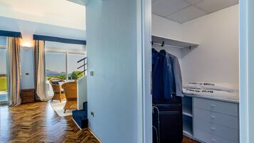 Quarto com piso de madeira, cama com etiqueta de travesseiro, guarda-roupa e vista para o exterior.