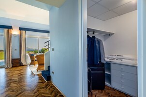 Quarto com piso de madeira, cama com etiqueta de travesseiro, guarda-roupa e vista para o exterior.