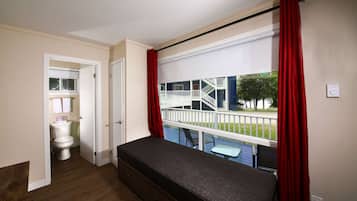 Quarto com uma grande janela, um banco e vista para uma varanda e área externa.