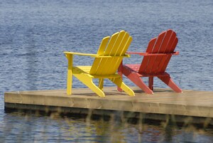 Duas cadeiras Adirondack em um píer de madeira sobre a água.