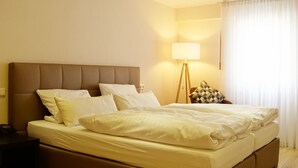 Quarto de hotel com uma cama grande, uma luminária de cabeceira e uma mesa de apoio.