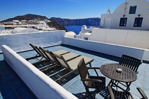 Terraço no telhado com piscina, espreguiçadeiras e uma mesa.