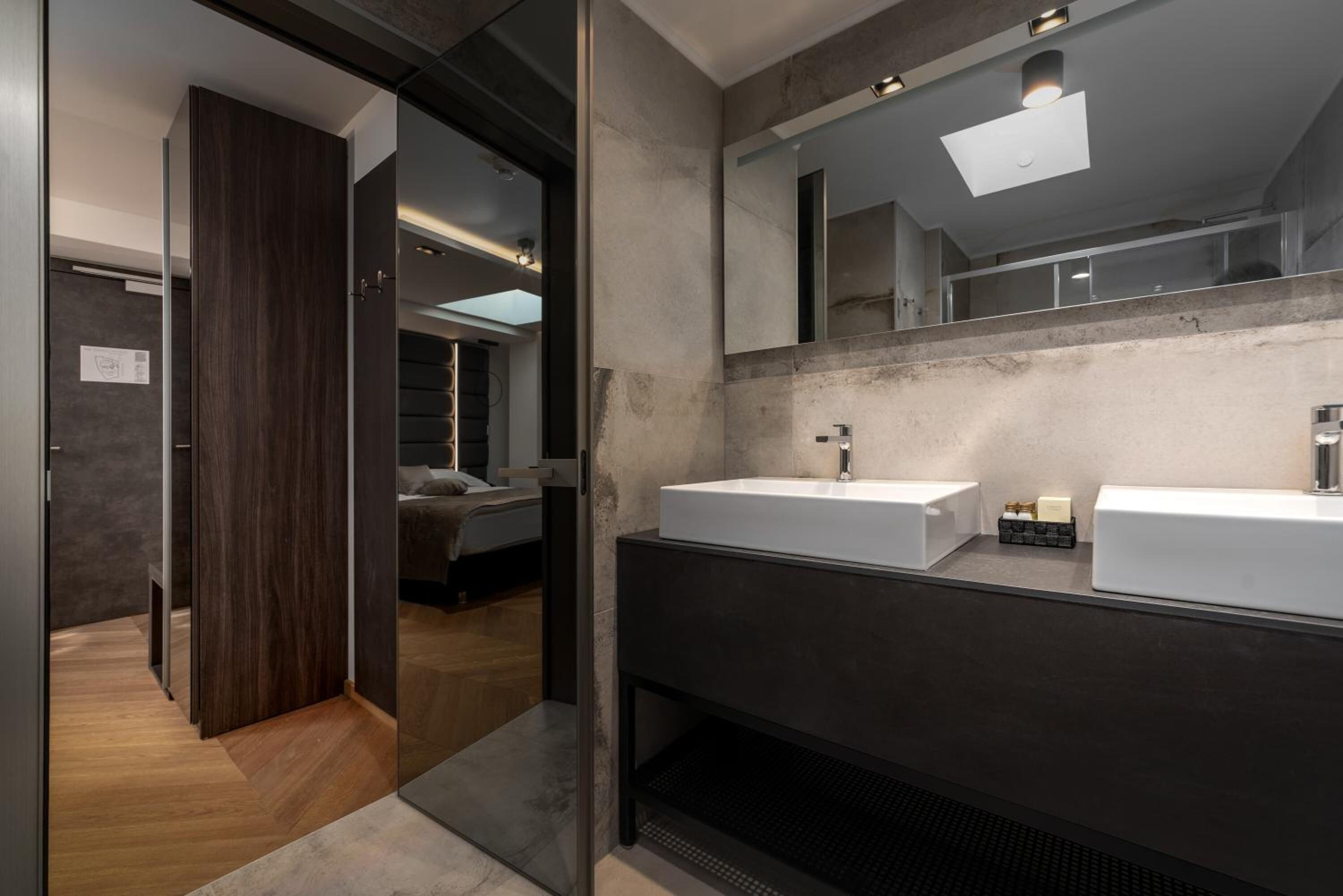Uma casa de banho moderna com duas pias, um espelho grande e uma porta de madeira que dá para um quarto.
