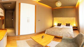 Quarto de hotel moderno com uma cama, uma escrivaninha, uma cadeira e um guarda-roupa.