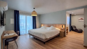 Quarto de hotel com cama, mesas de cabeceira, escrivaninha com cadeira, televisão e varanda com cortinas.