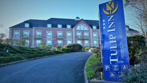 Entrada de hotel com uma placa indicando "Tulip Inn" e "Honfluer Residence".