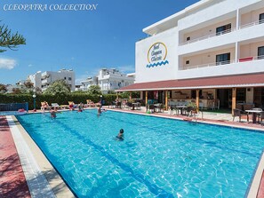 Um hotel com piscina, área de estar externa e uma placa com a inscrição 'Hotel Cleopatra Classic'.