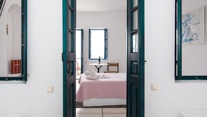 Quarto com cama, janela, cadeira e mesa pequena.