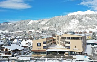 Um hotel com bar e restaurante, rodeado por edifícios cobertos de neve e montanhas.