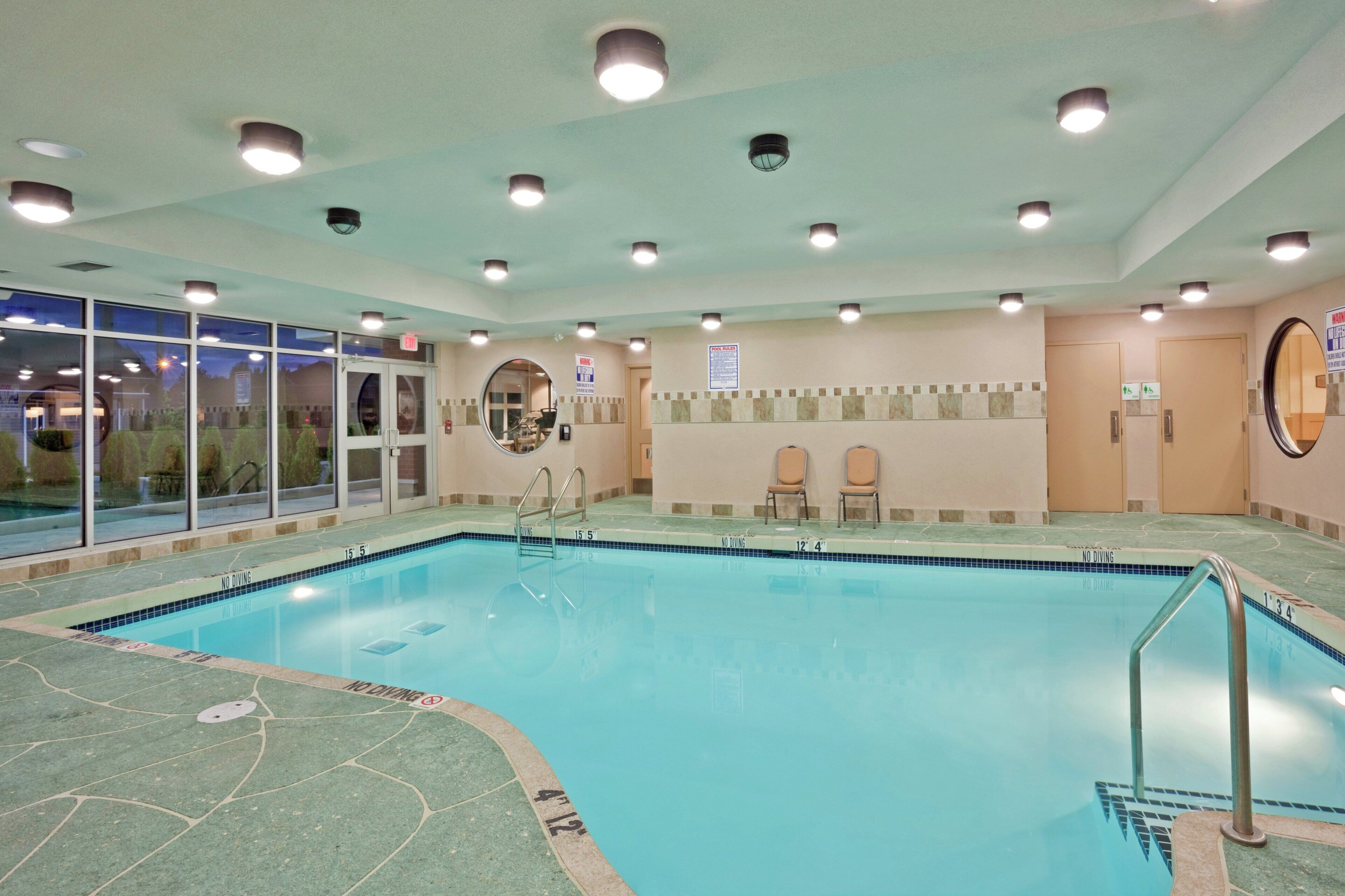 Piscina interior com água cristalina, marcações de profundidade e placas indicando que mergulhos não são permitidos.