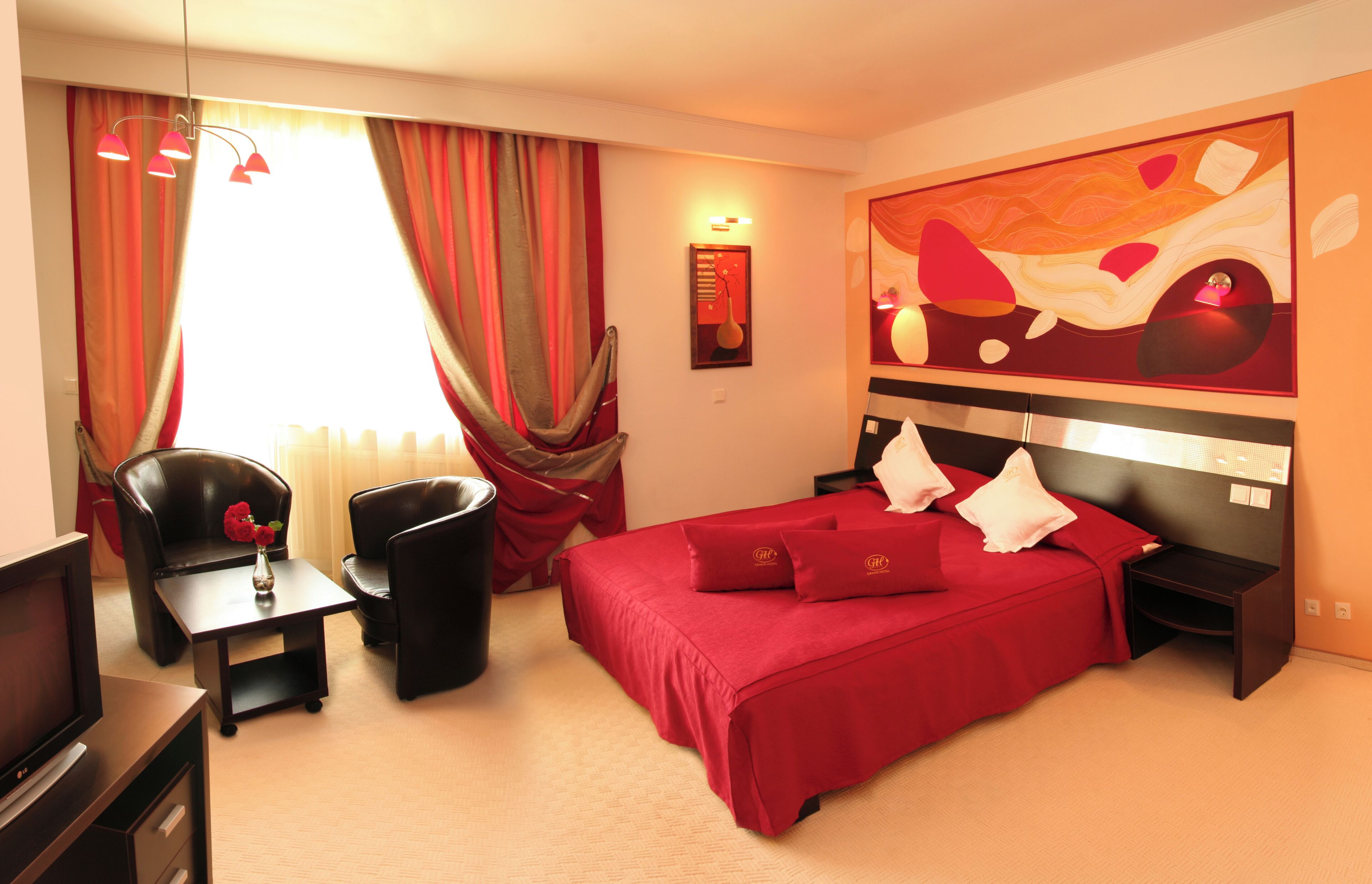 Quarto de hotel com cama, televisão, escrivaninha e cadeira.