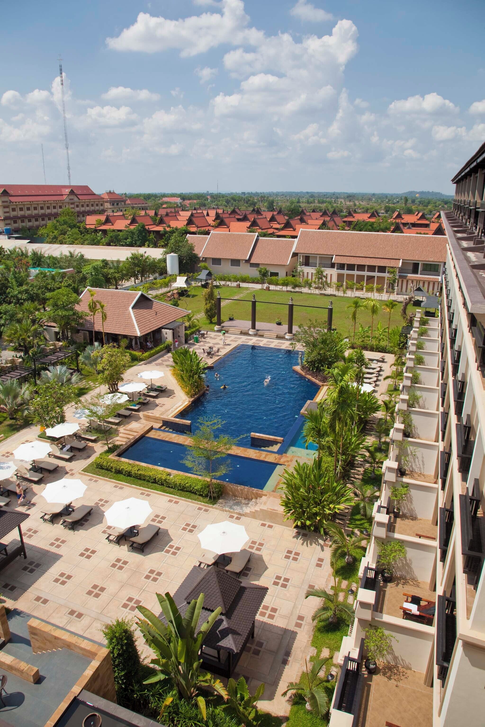 Um resort com piscina, espreguiçadeiras e vista dos edifícios ao redor.