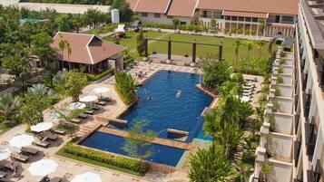 Um resort com piscina, espreguiçadeiras e vista dos edifícios ao redor.