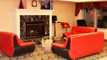 Sala de estar com lareira, sofás de couro vermelho, tapete estampado e uma árvore de Natal.