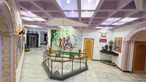 Um hall amplo com uma escultura decorativa de um cavalo no centro, um relógio e uma placa de boas-vindas.