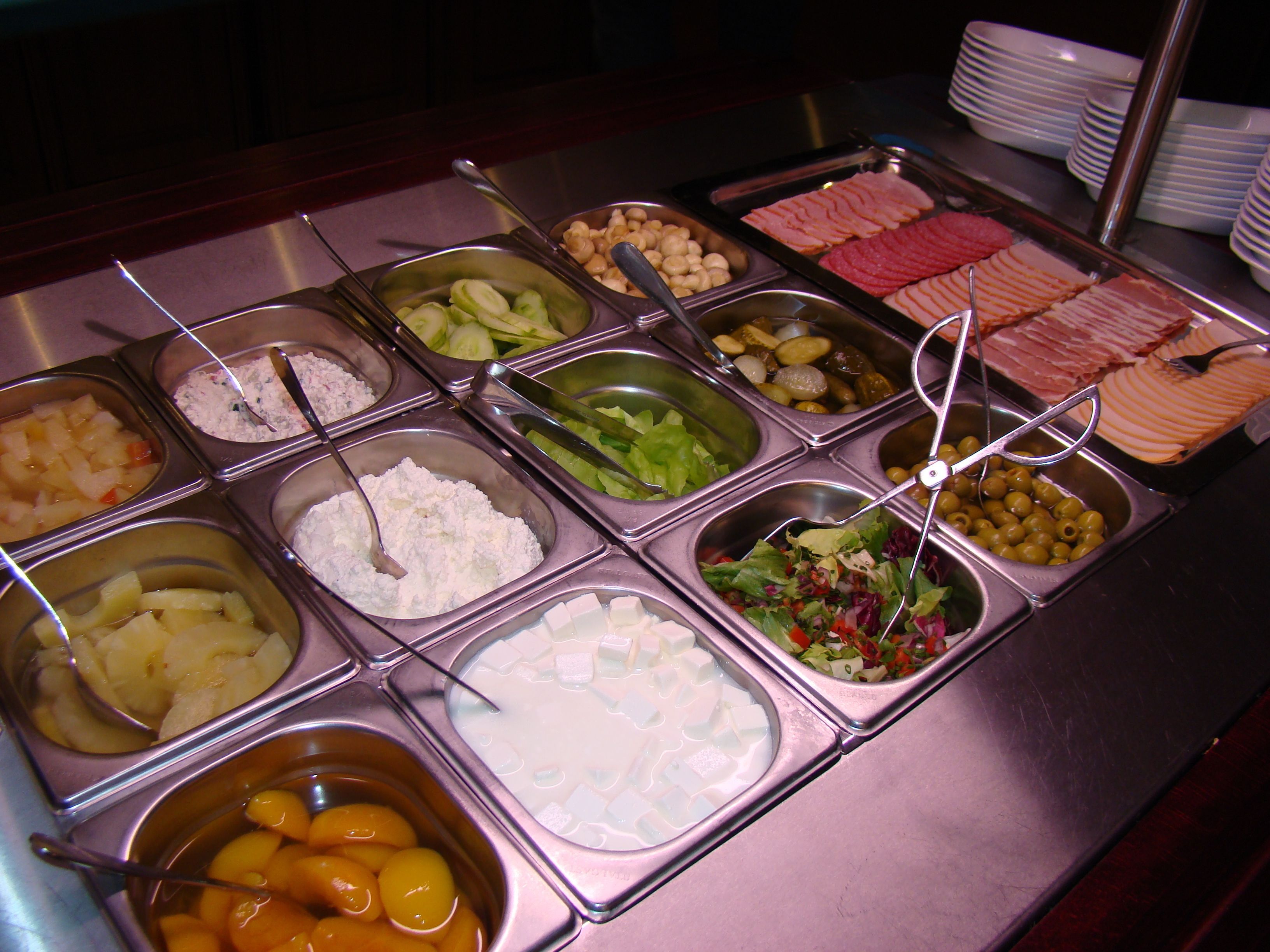 Buffet com diversas opções de alimentos, incluindo frutas, legumes e carnes.