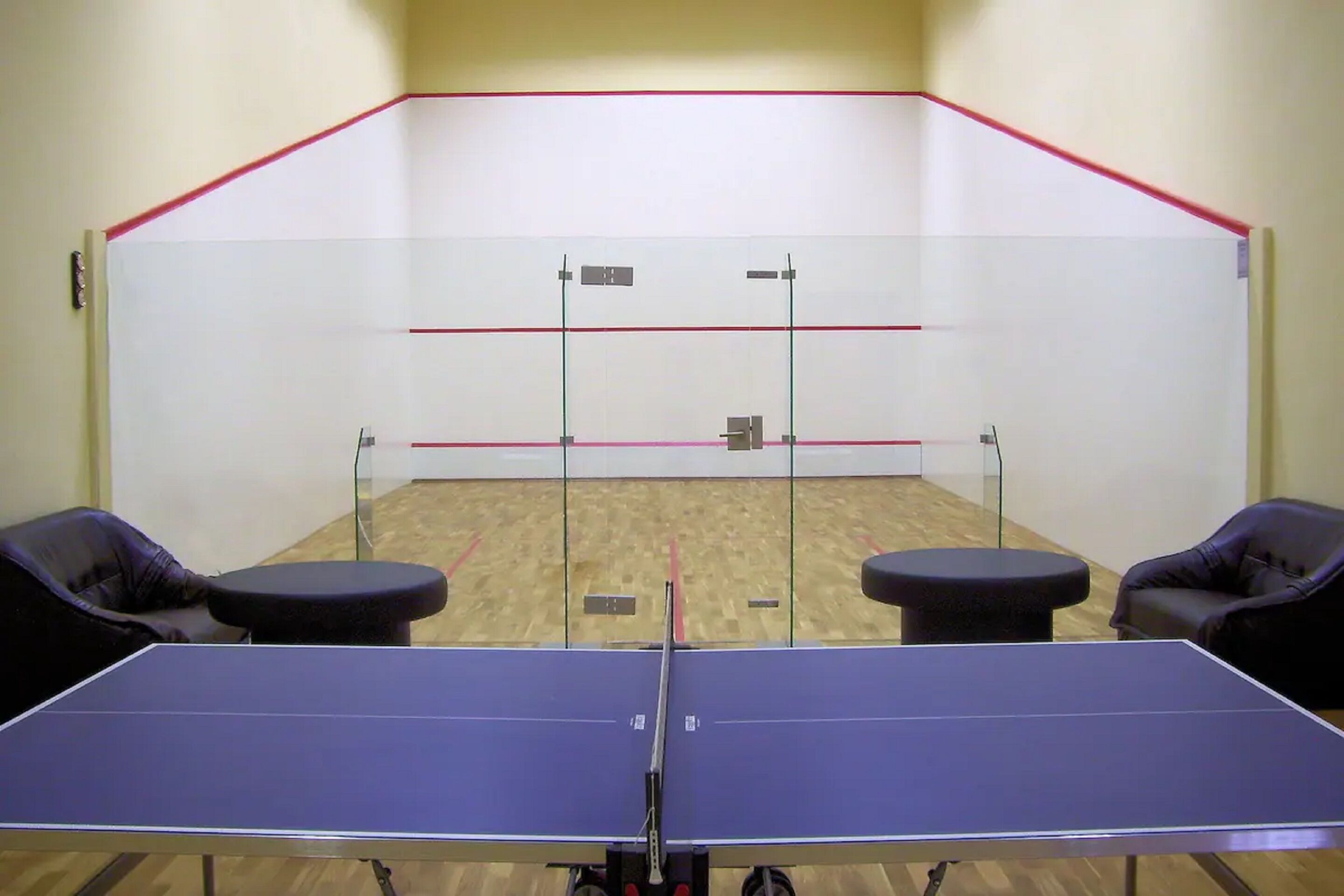 Uma quadra de squash com duas mesas e duas cadeiras.