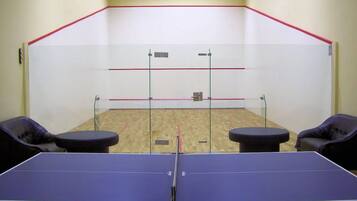 Uma quadra de squash com duas mesas e duas cadeiras.