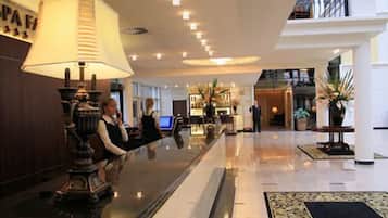 Um hall de hotel com uma mesa de recepção, uma luminária grande e um design de interiores moderno.