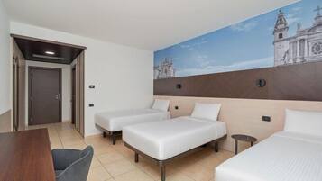 Quarto de hotel com duas camas, uma mesa, uma cadeira e uma porta.
