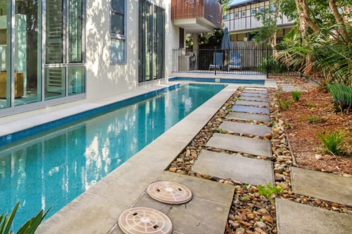 Uma casa moderna com piscina, janelas de vidro amplas e um caminho de pedra.