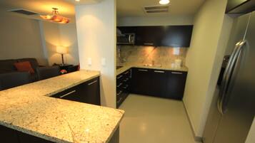 Cozinha moderna com bancadas de granito, armários escuros e eletrodomésticos de aço inoxidável.