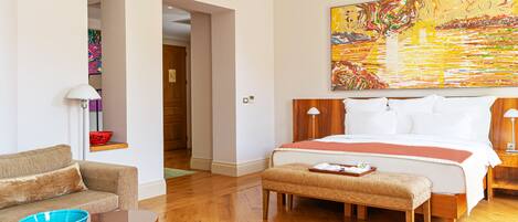 Quarto de hotel com uma cama grande, um sofá, uma mesa de centro e um quadro na parede.