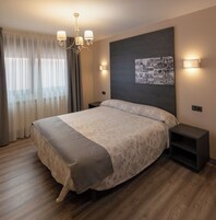 Um quarto moderno com uma cama grande, um candelabro, um quadro na parede e abajures.