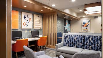 Espaço lounge moderno com uma mesa, duas cadeiras e um sofá.
