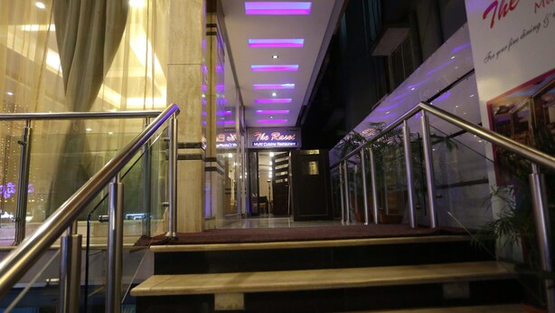 Uma escadaria com guarda-corpos de vidro que leva a um restaurante chamado "The Rasa".