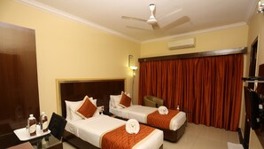Quarto de hotel com duas camas, uma mesa e uma cadeira.