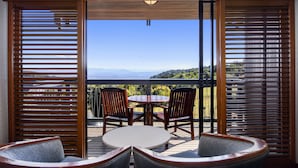 Uma varanda com mesa e cadeiras de madeira, com vista para uma paisagem montanhosa.