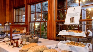 Buffet com diversos pães, doces e geleias.