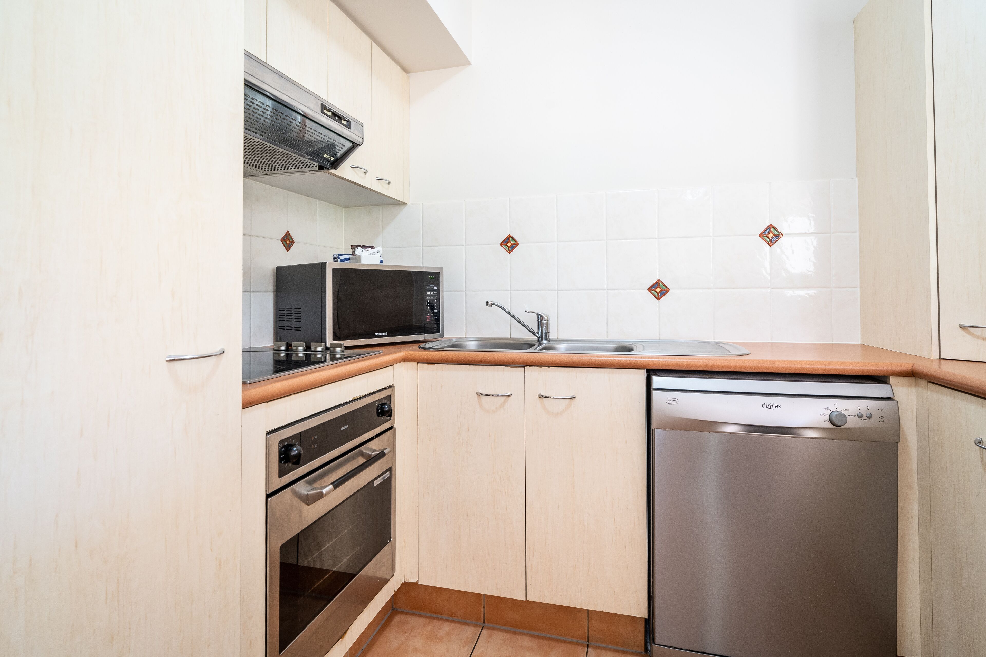 Cozinha compacta com micro-ondas, forno, máquina de lavar louça e pia.