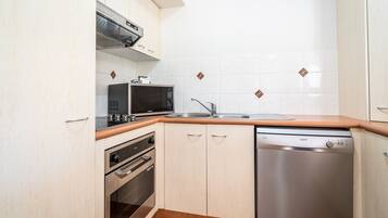 Cozinha compacta com micro-ondas, forno, máquina de lavar louça e pia.