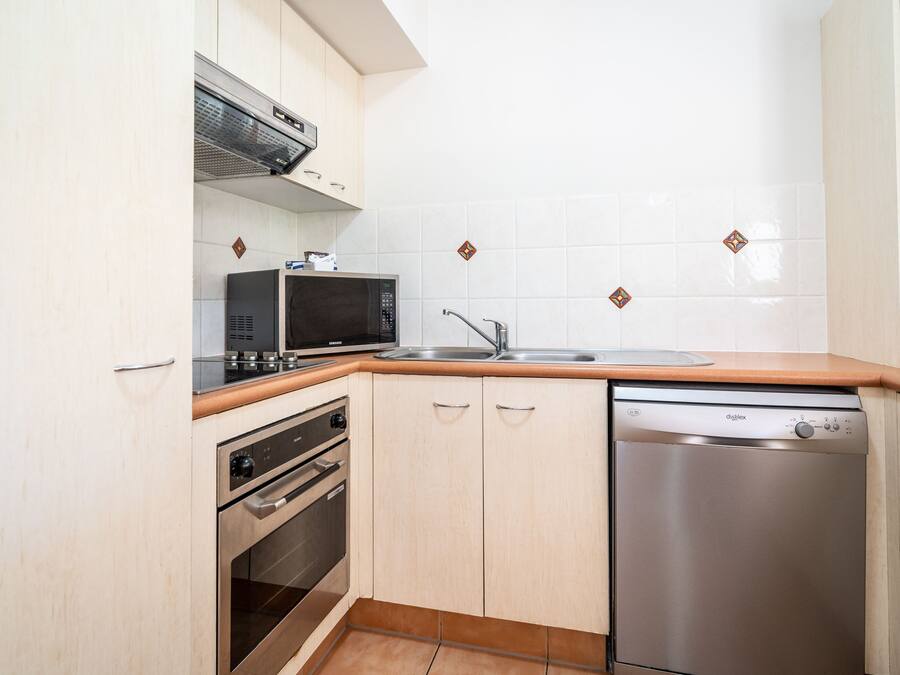 Cozinha compacta com micro-ondas, forno, máquina de lavar louça e pia.