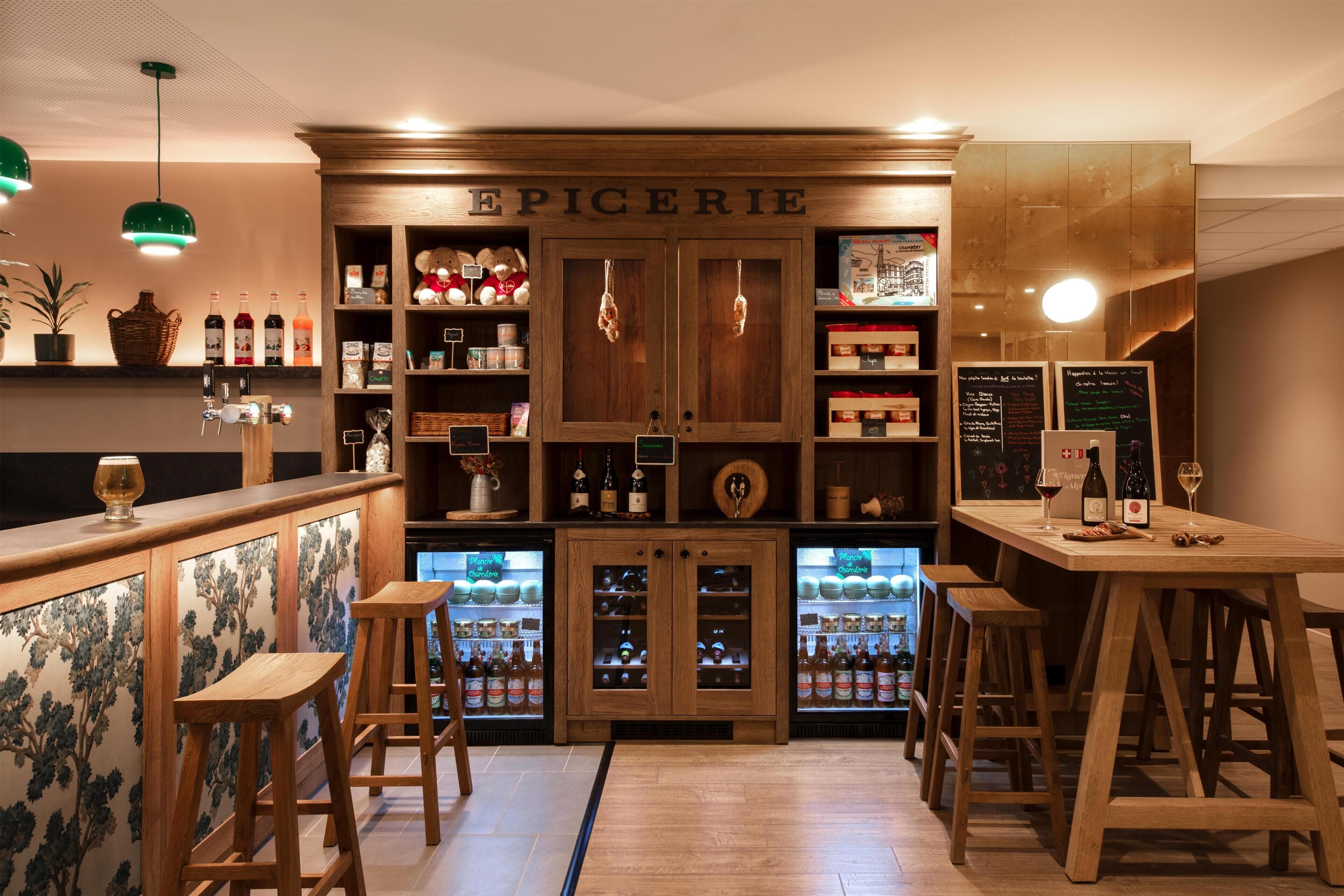 Uma área de bar com bancos de madeira, balcão e prateleiras cheias de garrafas e petiscos.