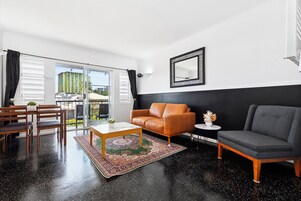 Uma sala de estar moderna com esquema de cores preto e branco, apresentando um sofá, uma poltrona, uma mesa de centro e uma pequena mesa lateral.