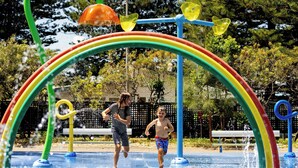 Uma área de lazer com água, um arco-íris e jatos d'água.